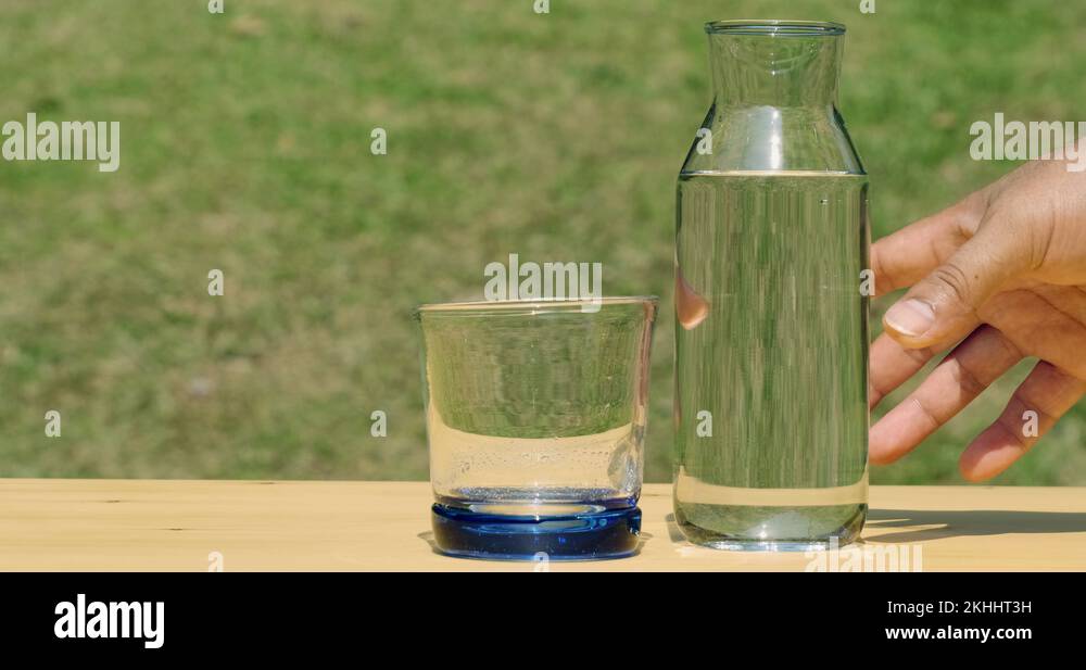 Human hand pick up the bottle and pouring pure water in to the glass ...