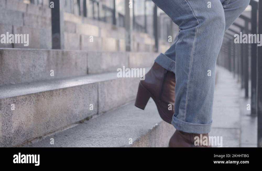 Close-up side view of female Caucasian legs stepping down the stairs ...