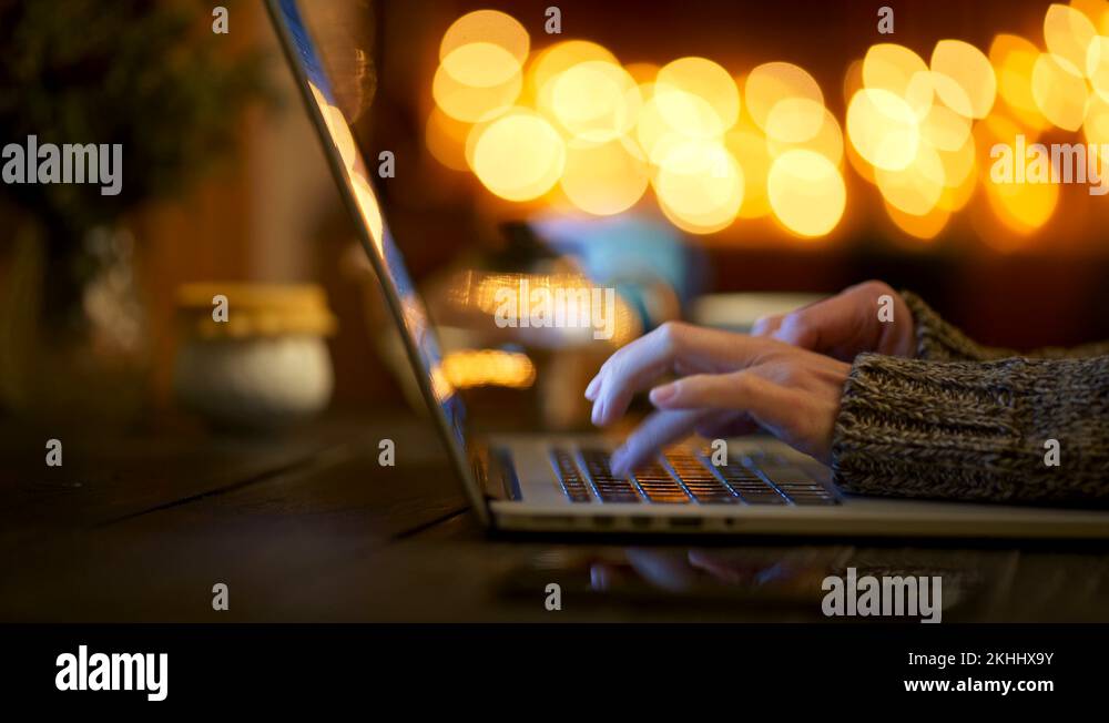 Woman wearing wool sweater typing fast with her fingers on her laptop ...