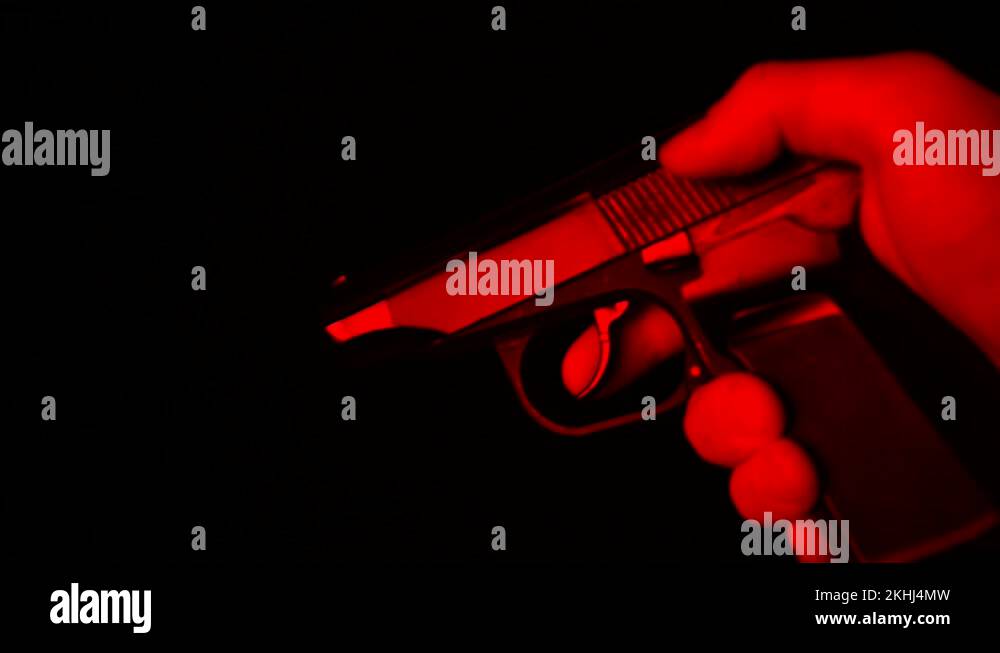 Horror scene of male hand with gun at red glowing light. Serial killer ...