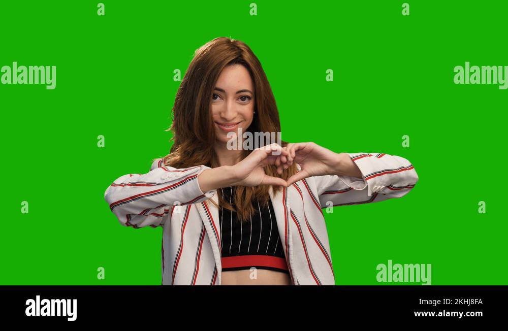Cute smiling girl pose on green screen showing heart and thumb up ...