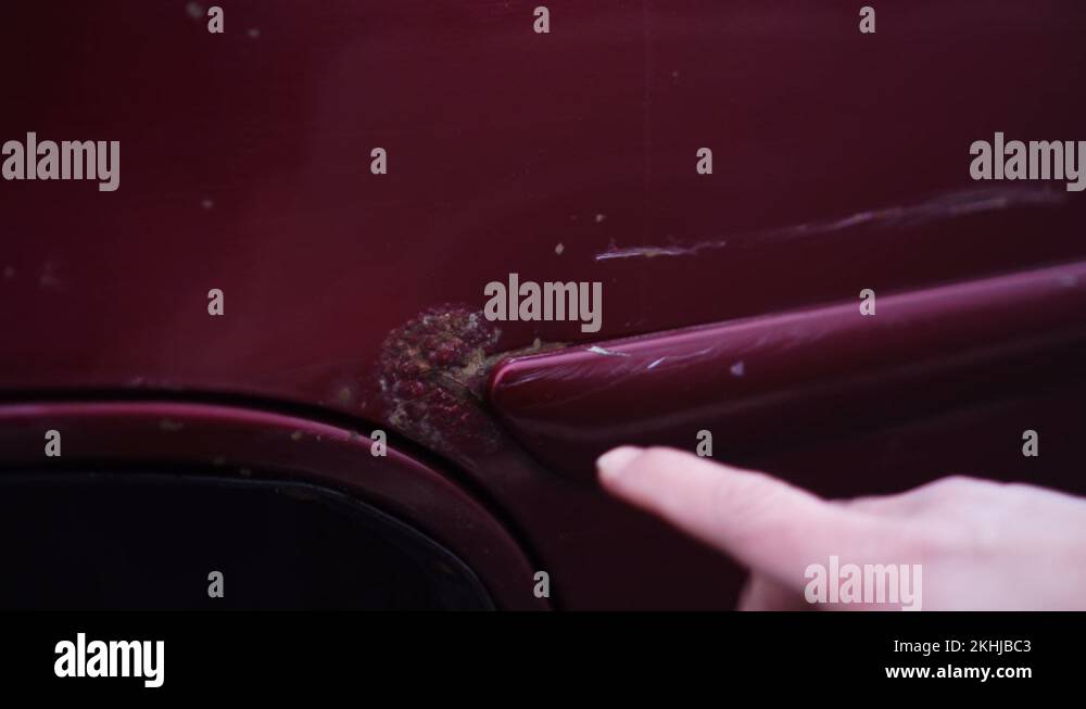 Man shows rust in a car paint. Finger points a scratch on red car Stock ...