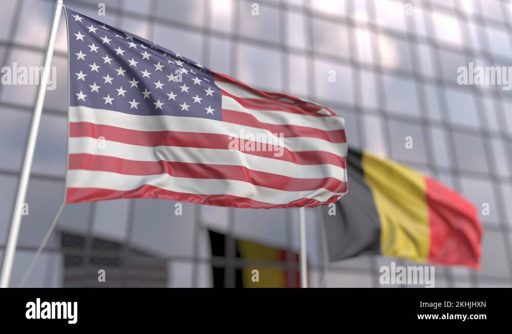 Waving flags of the USA and Belgium in front of a modern skyscraper ...