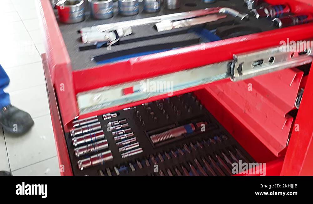 man puts the tools into the holes in tool box, red iron chest in car ...