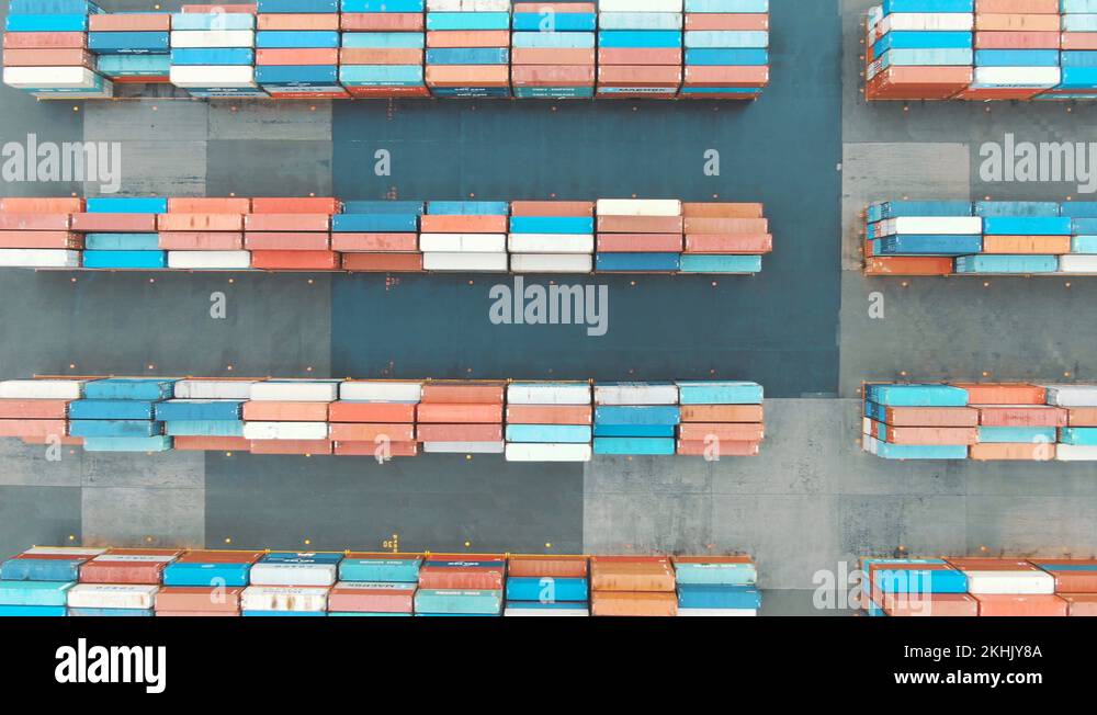 Sea cargo containers stand in straight rows in an open-air warehouse ...