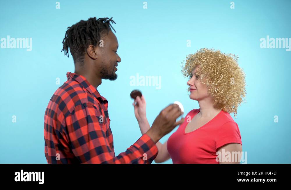 African Man Caucasian Woman Eating Black And White Marshmallows Blue