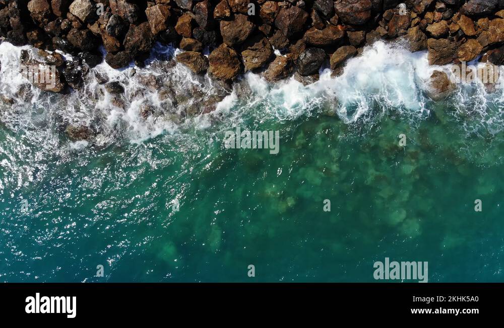 Sea water wash and splash on stones of breaker, top down view, camera ...