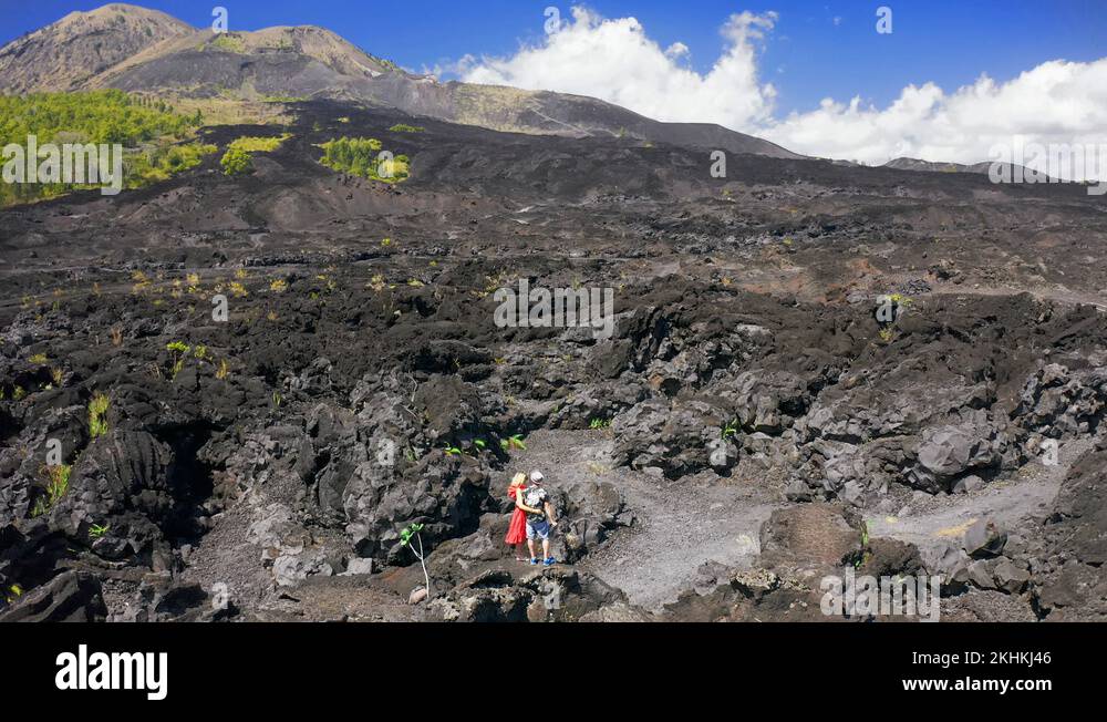 Young couple man and woman hikers on black lava field on volcano Batur ...