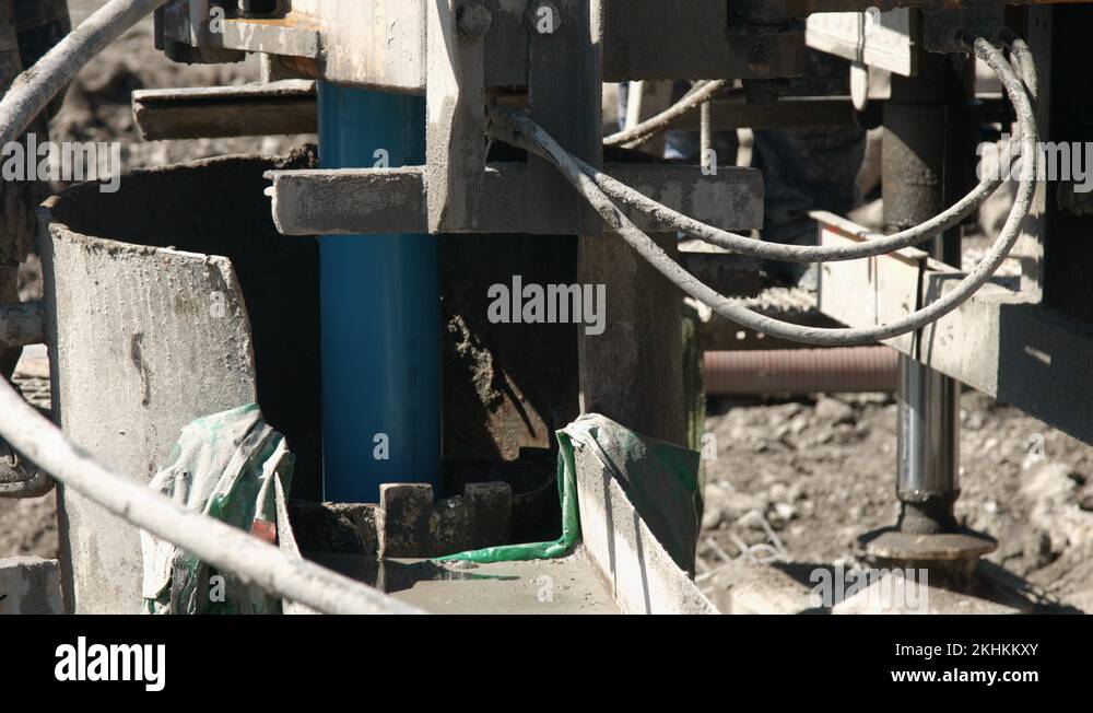 Drilling rig installing plastic water tubes to protect drilled well ...