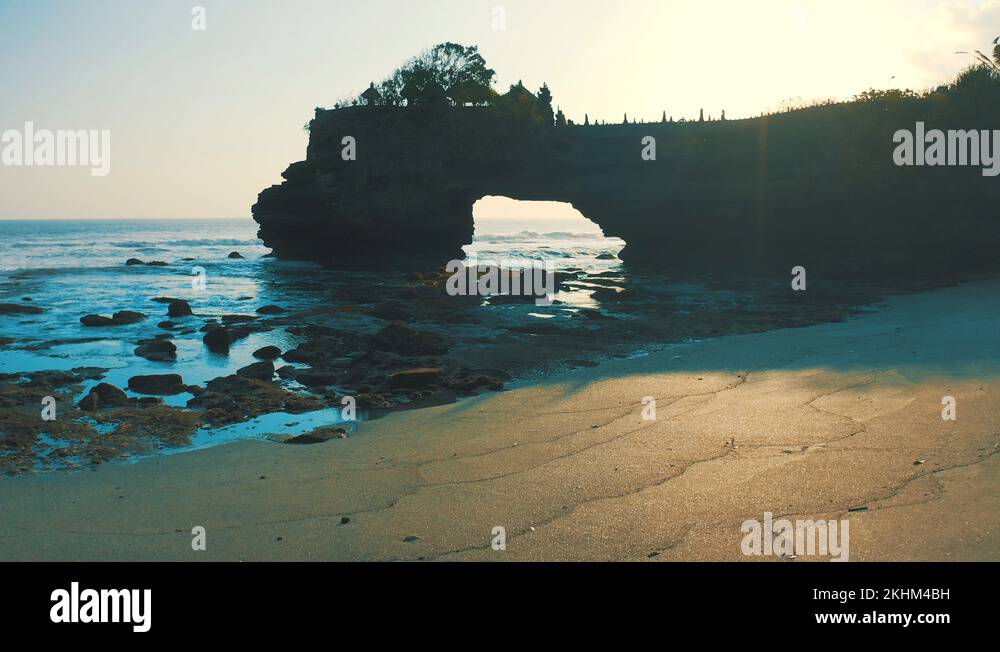 Pura Batu Bolong on the edge of a cliff at coastline with hole in the ...