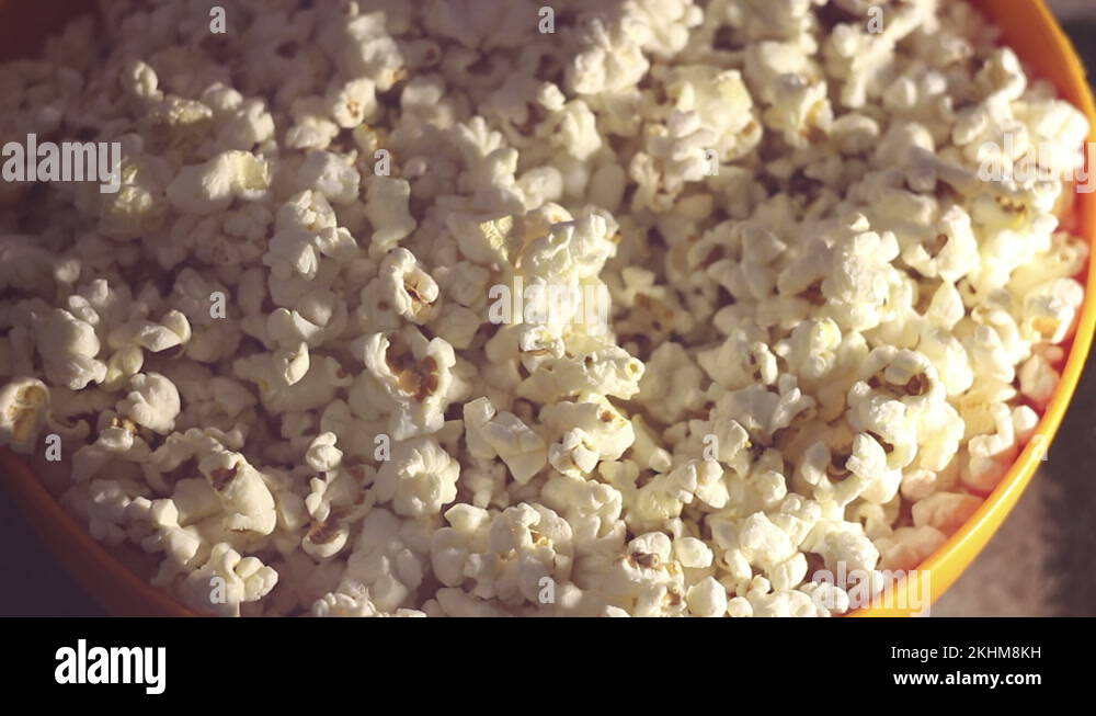 A man grabs popcorn from a bucket while watching TV Stock Video Footage ...
