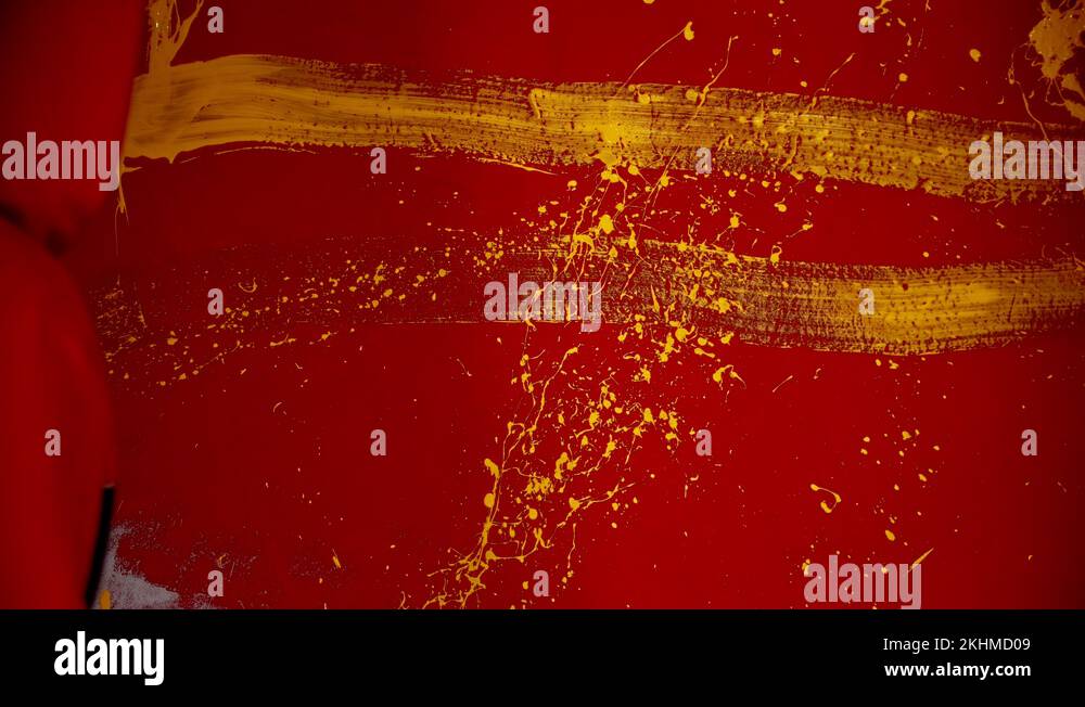 A man walking by the red wall and painting lines with a yellow color using a Stock Video Footage ...