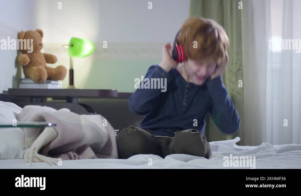 Little Caucasian boy shaking head emotionally as listening to rock ...