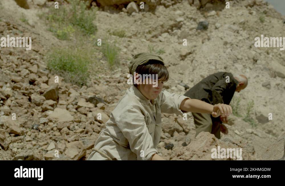 Young miner boy is working in a quarry . Many workers are mining with ...