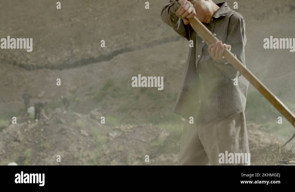 Young miner boy is working in a quarry . Many workers are mining with ...