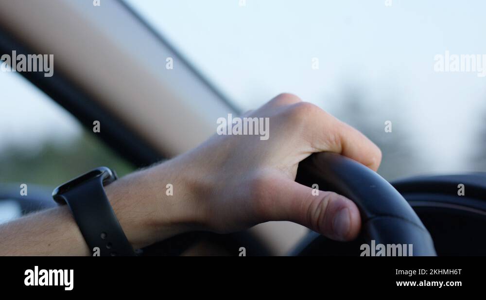 Man hand holding steering wheel in car as he drives - close up on one ...