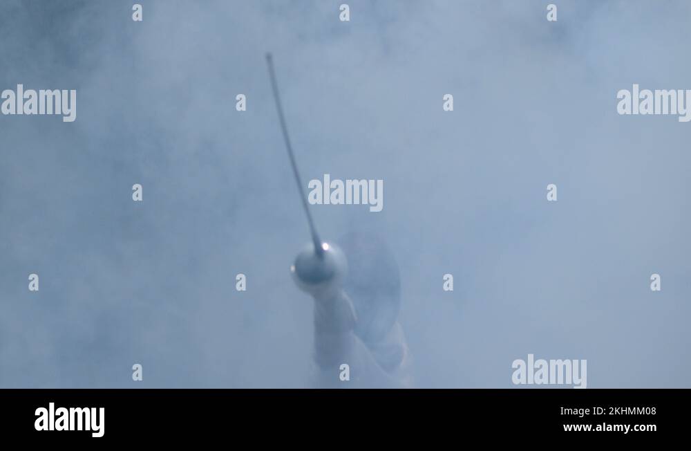 Professional fencer in uniform practicing maneuvers with sword in dark ...