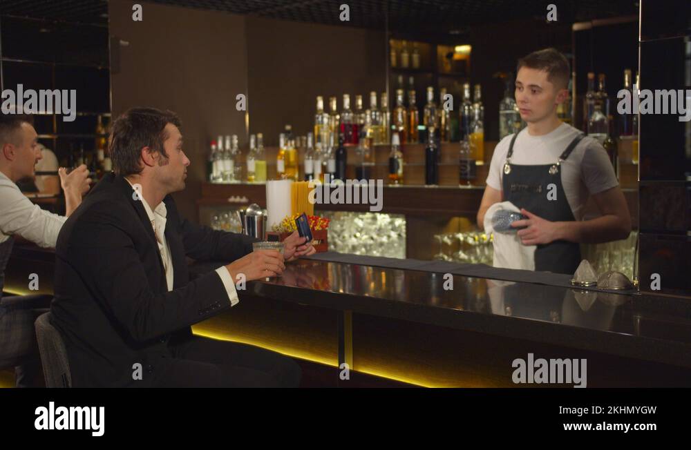 Man sits at the bar, talks to bartender and smiles to someone Stock ...