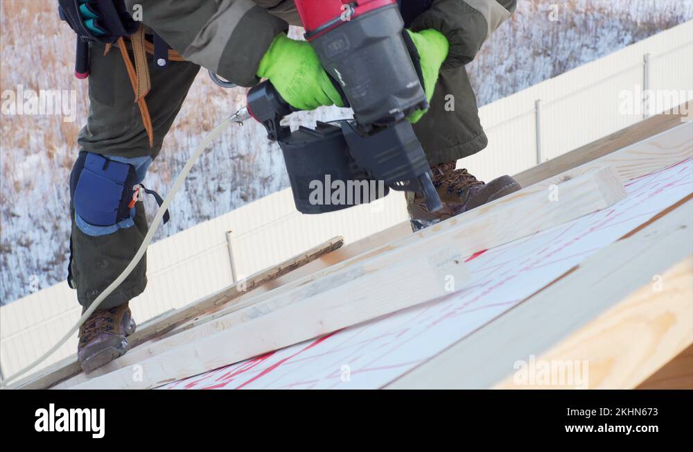 Builders apply waterproofing layer on roof with hammer. Frame house ...