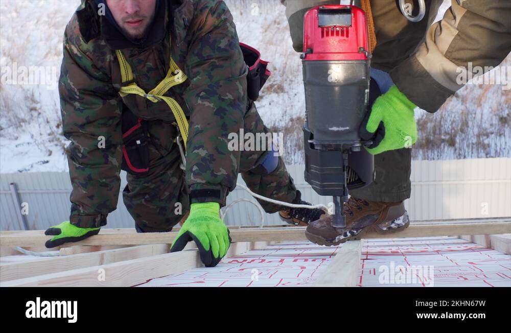 Builders apply waterproofing layer on roof with hammer. Frame house ...
