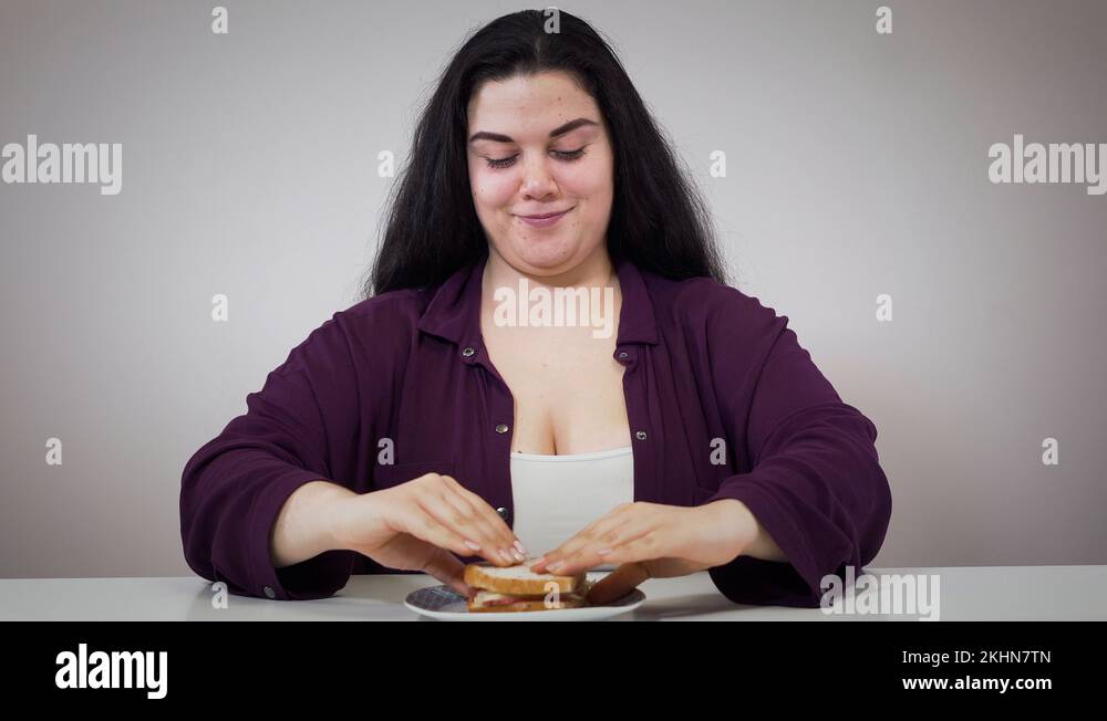 Positive Caucasian obese girl eating sandwich. Plump woman with ...