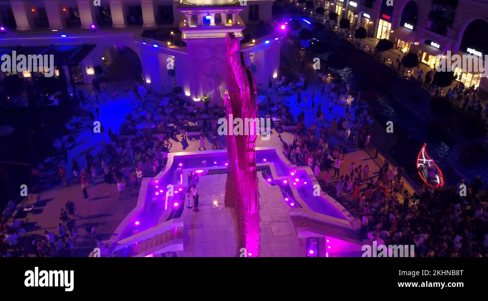 Massive crowd of people is gathering around a big stage with purple ...