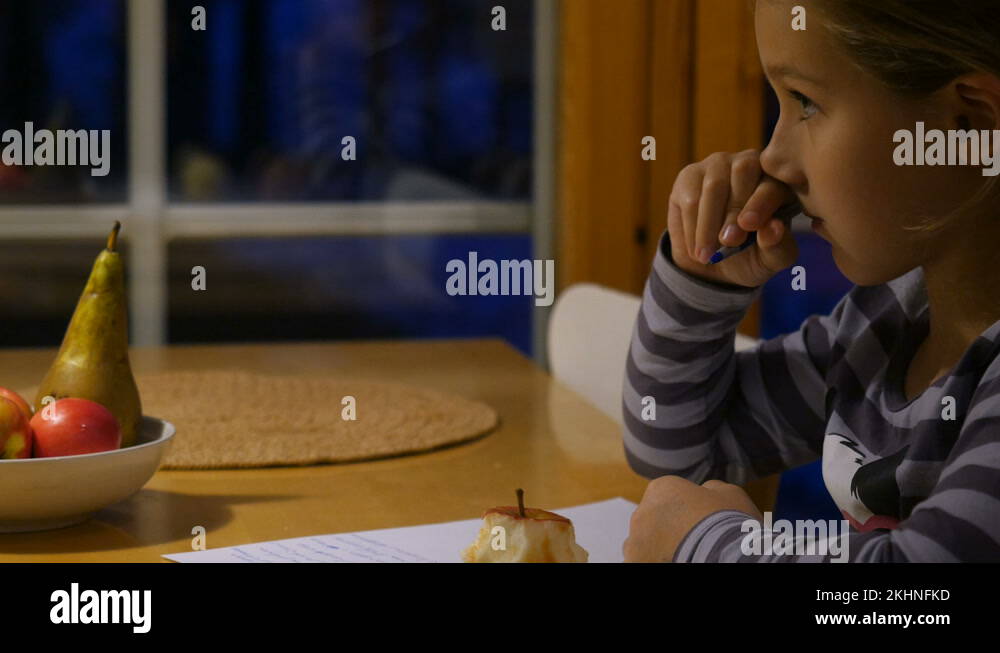 Pretty school girl at home, writing a homework. Child sitting at table ...