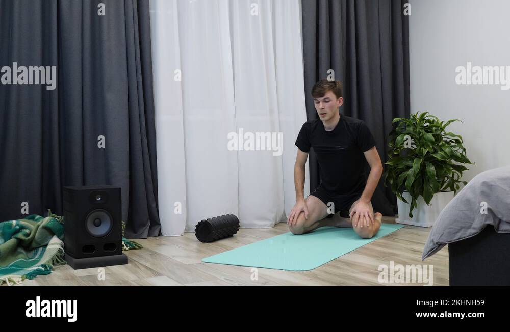 Young athlete stretches hip muscles, hamstring muscles on yoga mat ...