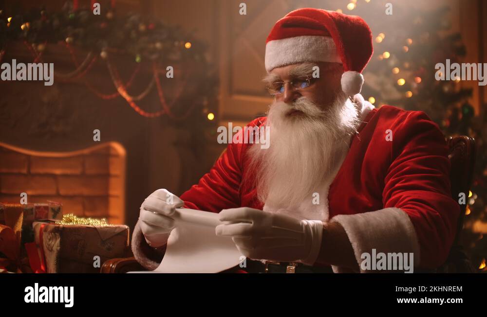 Santa Claus rolls up a parchment scroll in magic light against the ...