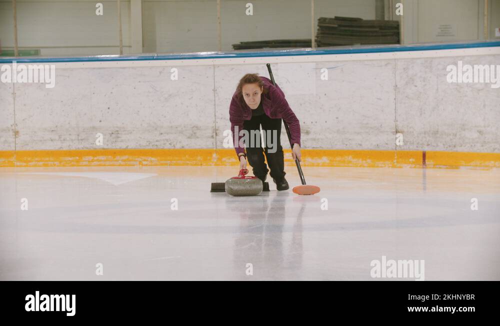 Curling - a woman in glasses skating and leading a granite stone on the ...