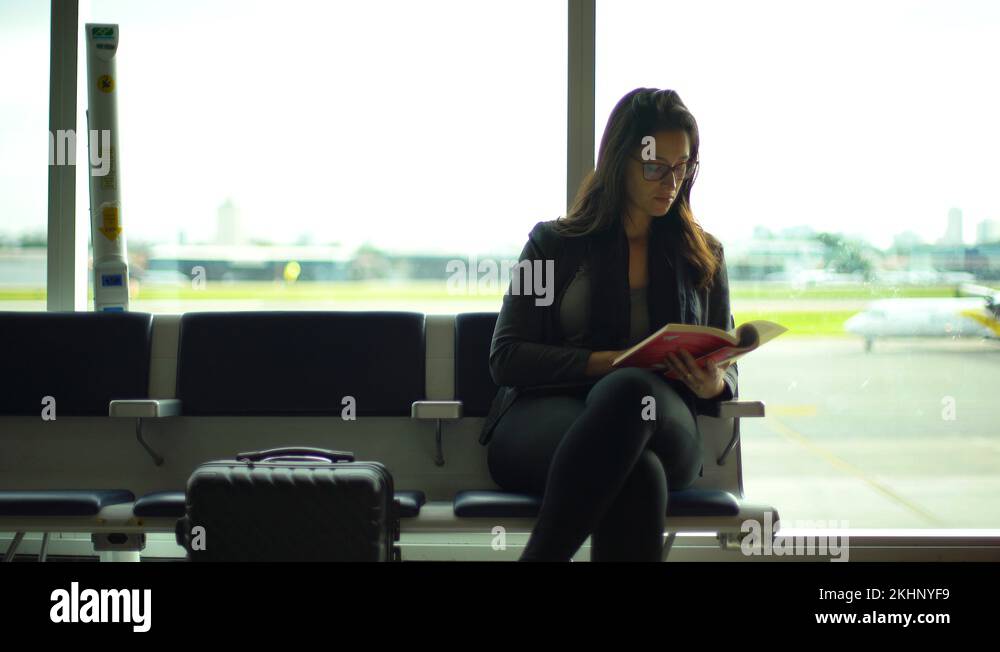 Relaxed woman waiting for flight at lounge area of airport reading a book Stock Video Footage ...
