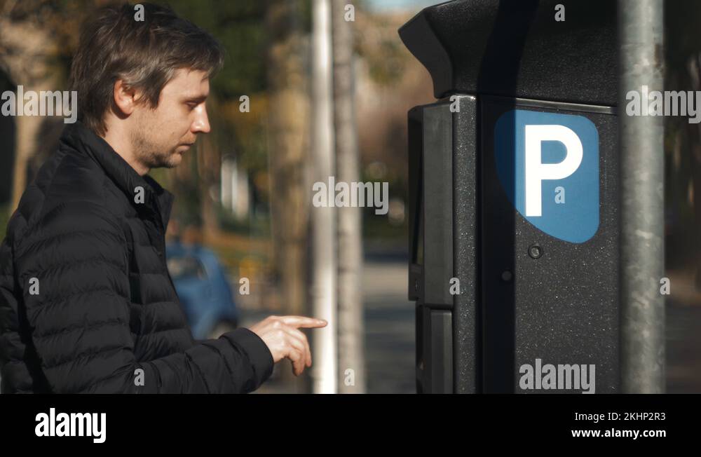 man inserting a parking lot ticket at an automated pay machine pay with ...