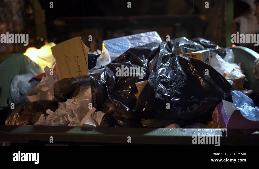 Garbage truck with garbage man at work on rainy city street at night ...