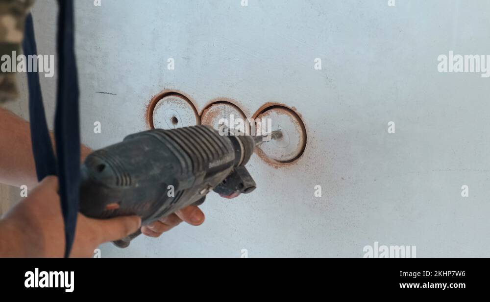 Builder making holes in brick wall with drill, place for electrical ...