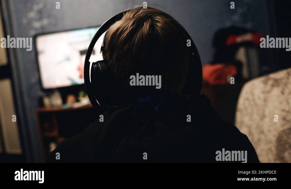 The boy is playing a game console.Rear view. The camera is in motion ...