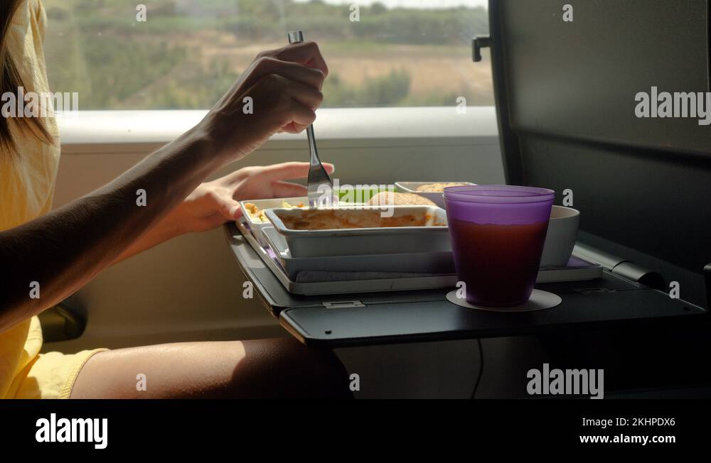 An attractive caucasian girl eating delicious food in high speed train ...