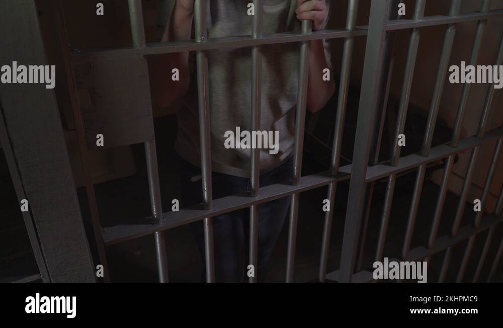 Female Prisoner / Inmate behind bars in a Jail / Prison Cell. Tilt Shot ...