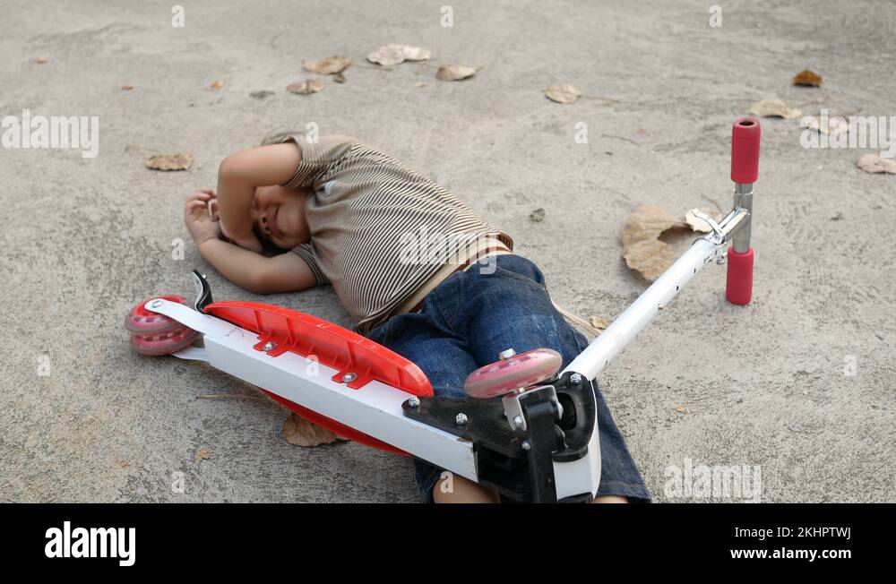 Cute Asian little girl lying on the ground after falling off her ...