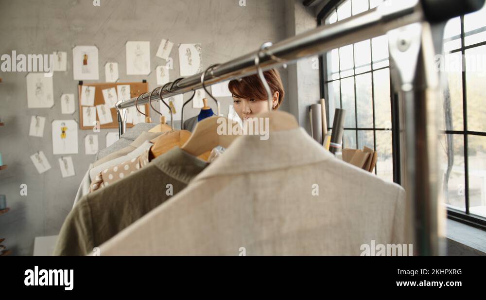 Authentic fashion designer looking through clothes on hanger, picking ...
