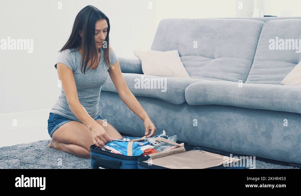 Mom is packing a huge blue suitcase. Little girl is hepling her ...