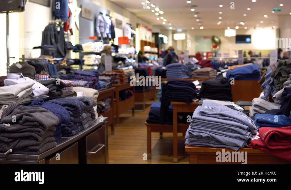 Clothes displayed in a clothing store, people look at the clothing in ...