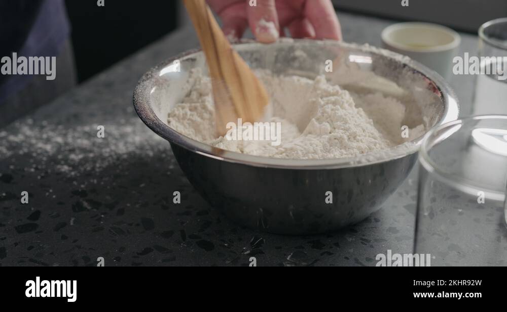 Slow motion man mixing dry ingredients with flour in steel bowl on ...