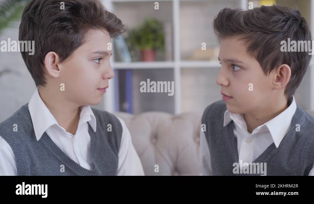 Close-up side view of two identical twin brothers looking at each other ...