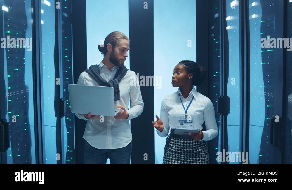 IT supervisor woman walking with server technician through data center ...