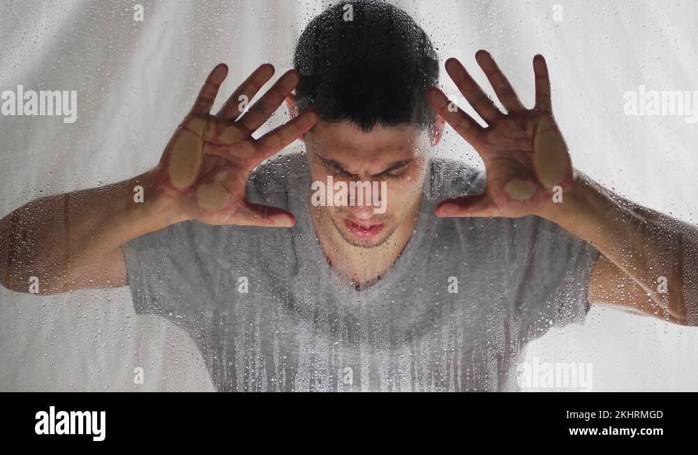 guy is sad with his elbows leaning on window through which drops are ...