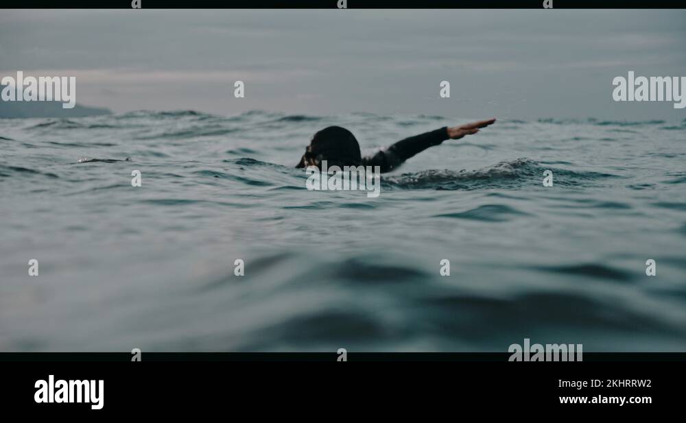 Tired swimmer swimming in ocean in wave storm . Female triathlon ...