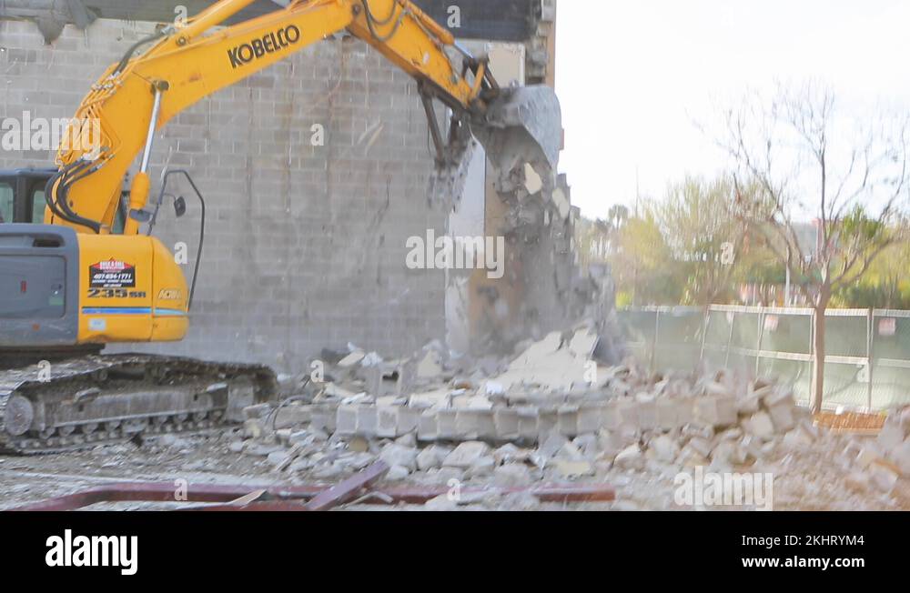 Heavy equipment tears down cinder block wall at demolition site Stock ...
