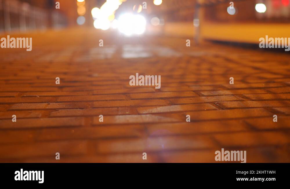 Night city street, surface level of dark stone tile sidewalk pavement ...