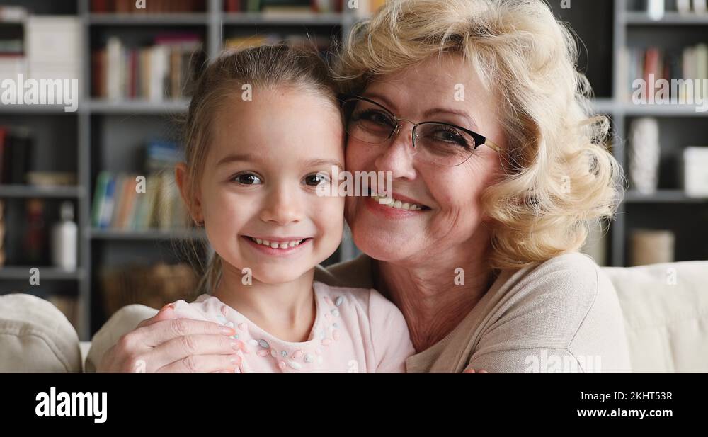 Happy Older Grandma Hug Cuddle Cute Granddaughter Look At Camera Stock