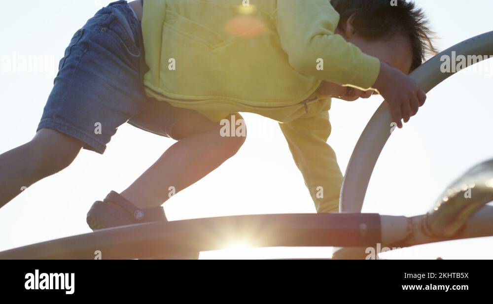 Toddler boy holding on to play structure as he builds up courage to ...